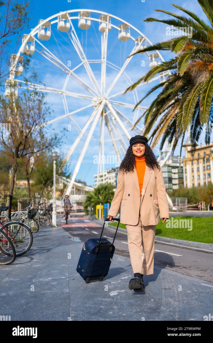 Vertical photo of a chic latin tourist arriving at a city with a Ferris ...