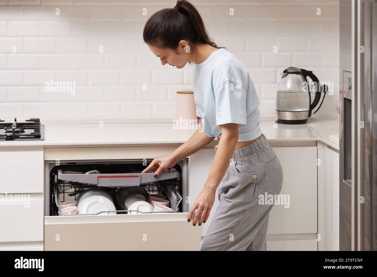 pretty woman loading dishes to open automatic built-in dishwasher ...