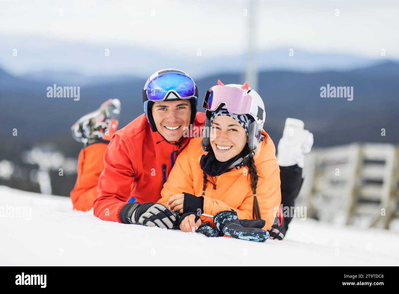 Ski friends lying on the snow. Couple in love posing outdoors. Skier ...