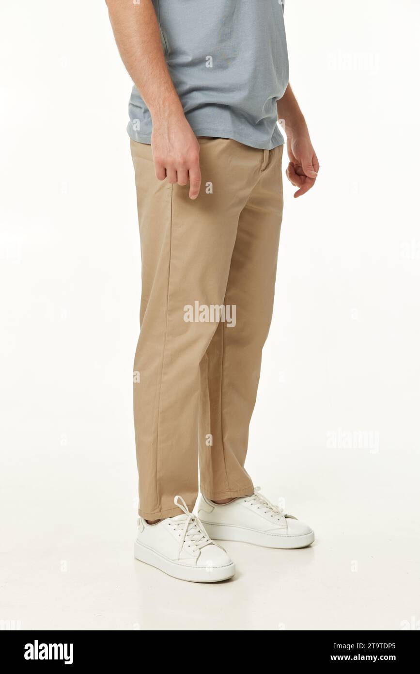man wearing white sneakers and casual beige pants on studio background ...
