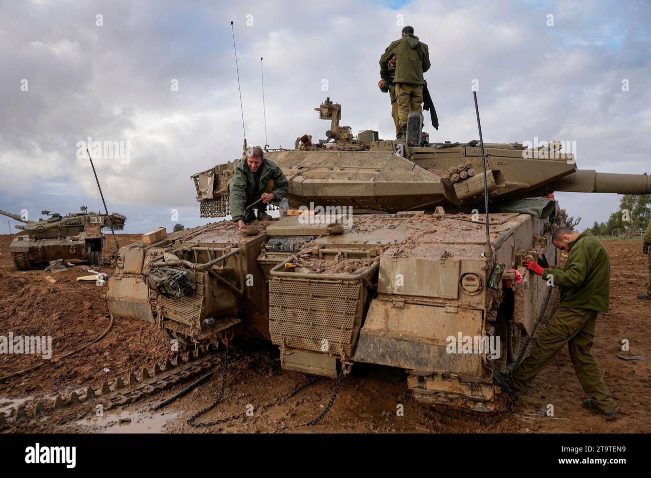 Israeli soldiers work on a tank at an army staging area near Israel's ...