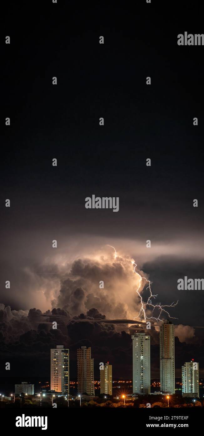 Lightning striking tall skyscrapers in the city at night during a ...