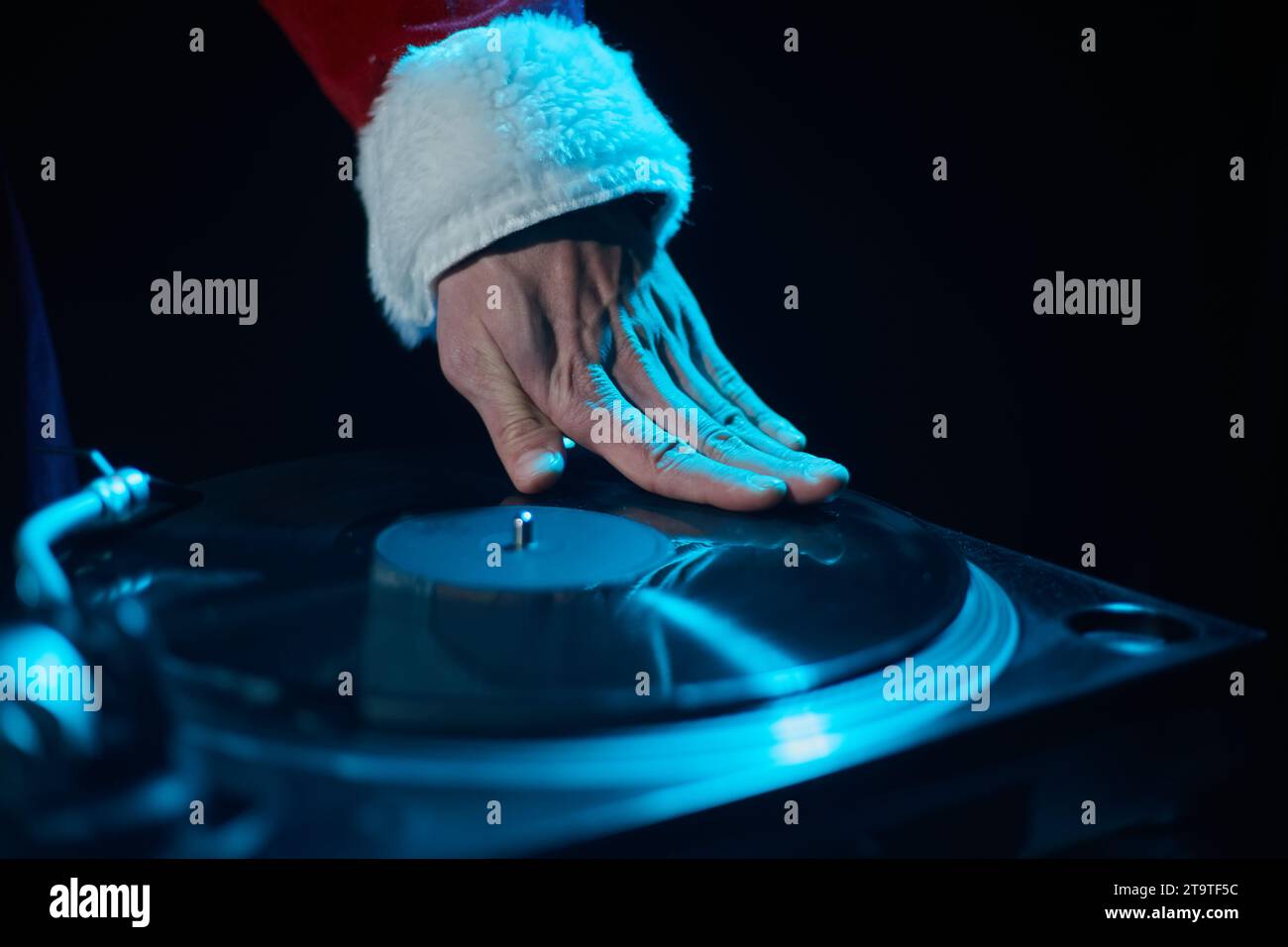 Hip hop DJ in red Santa costume scratching a vinyl record on turntable ...