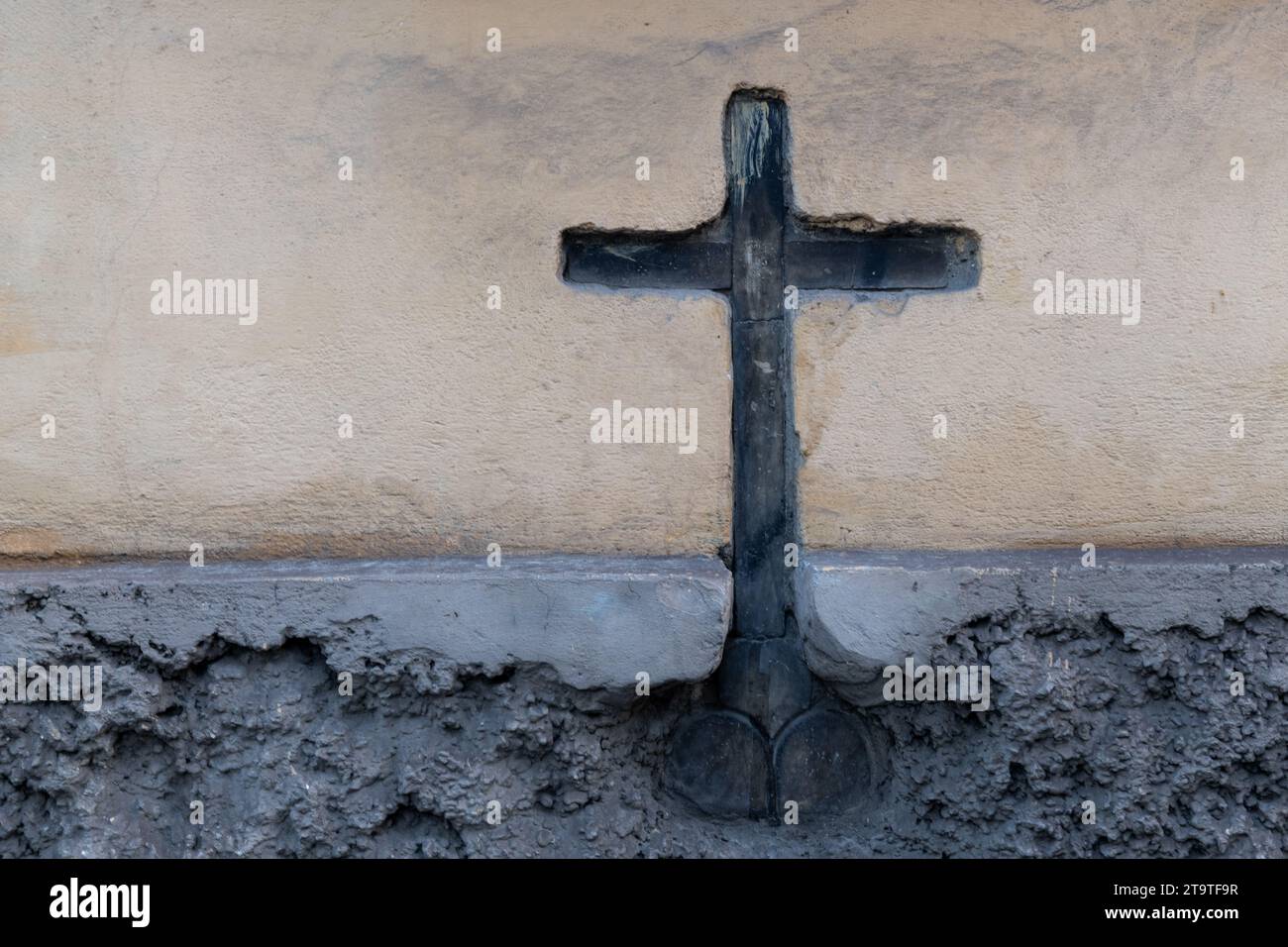A wooden cross is embedded into a hollowed out section of a stucco and ...