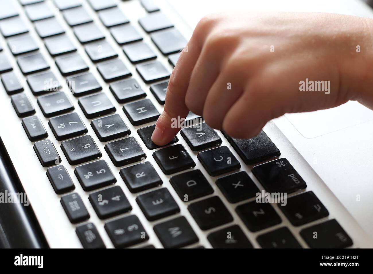 A general view of a young child typing with one finger on a laptop ...