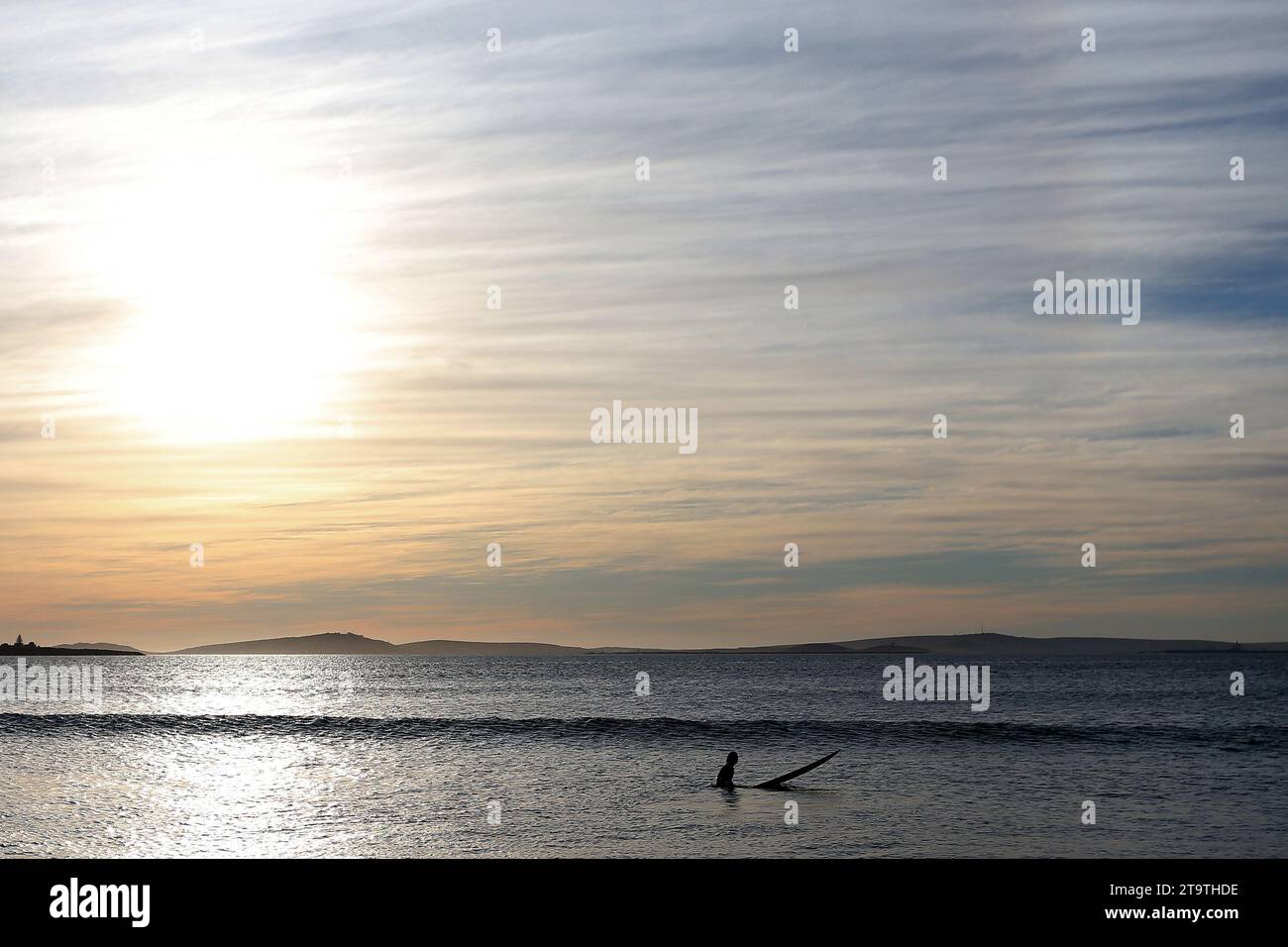 A lone surfer waits for the next set of waves as the sunsets in ...