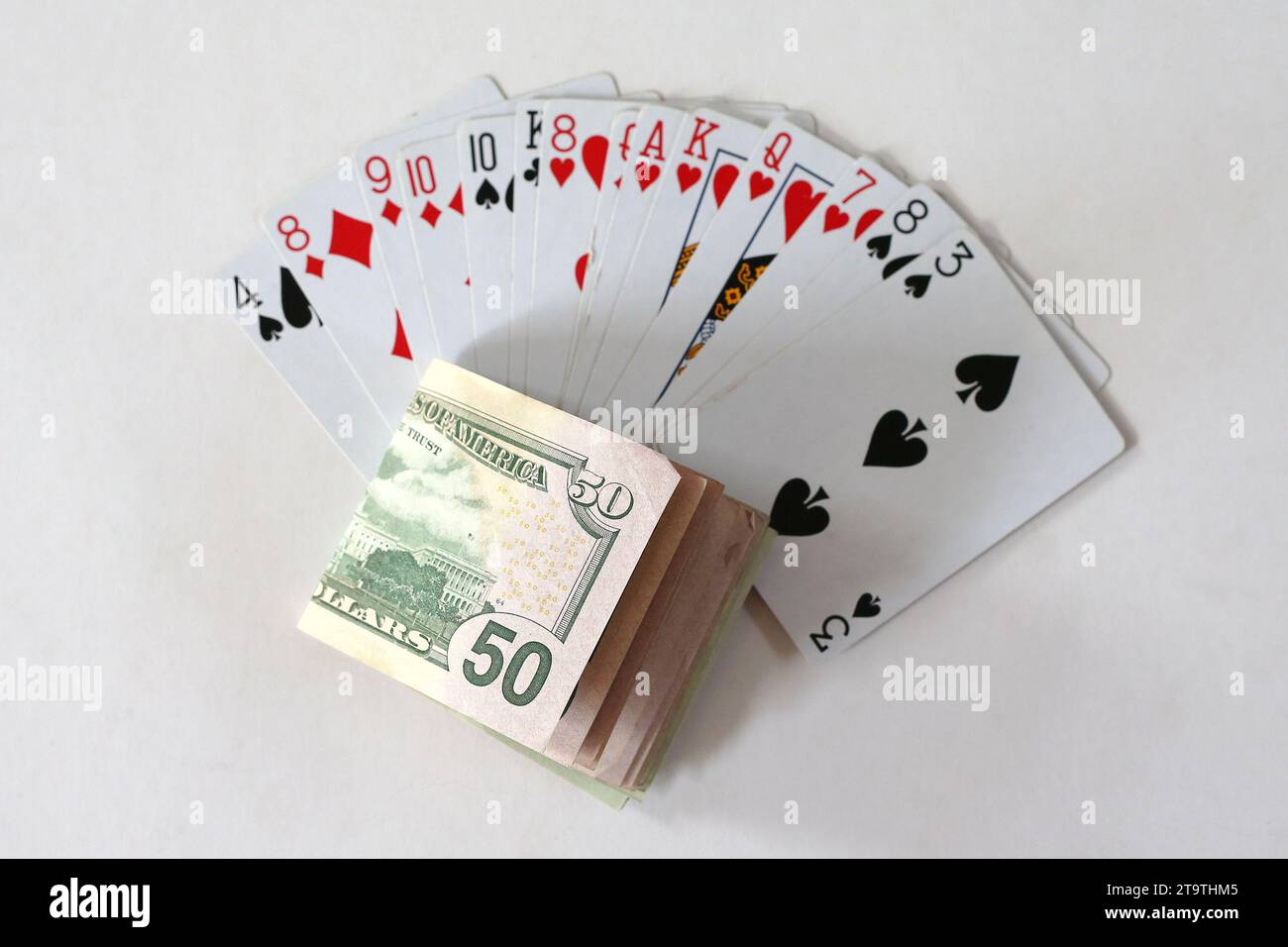 A wad of dollar notes with some playing cards Stock Photo - Alamy