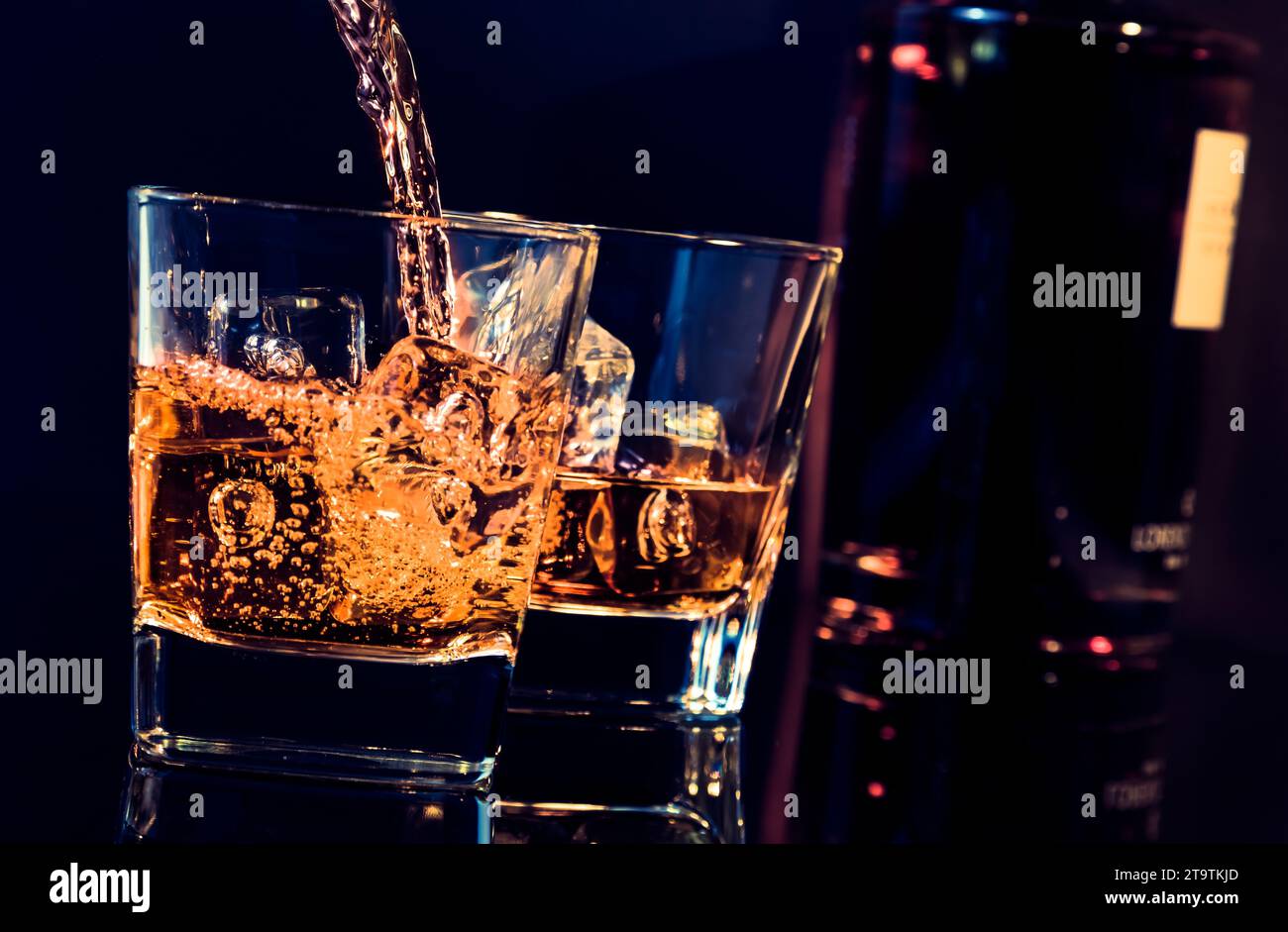 barman pouring whiskey in front of whiskey glass and bottle on black ...