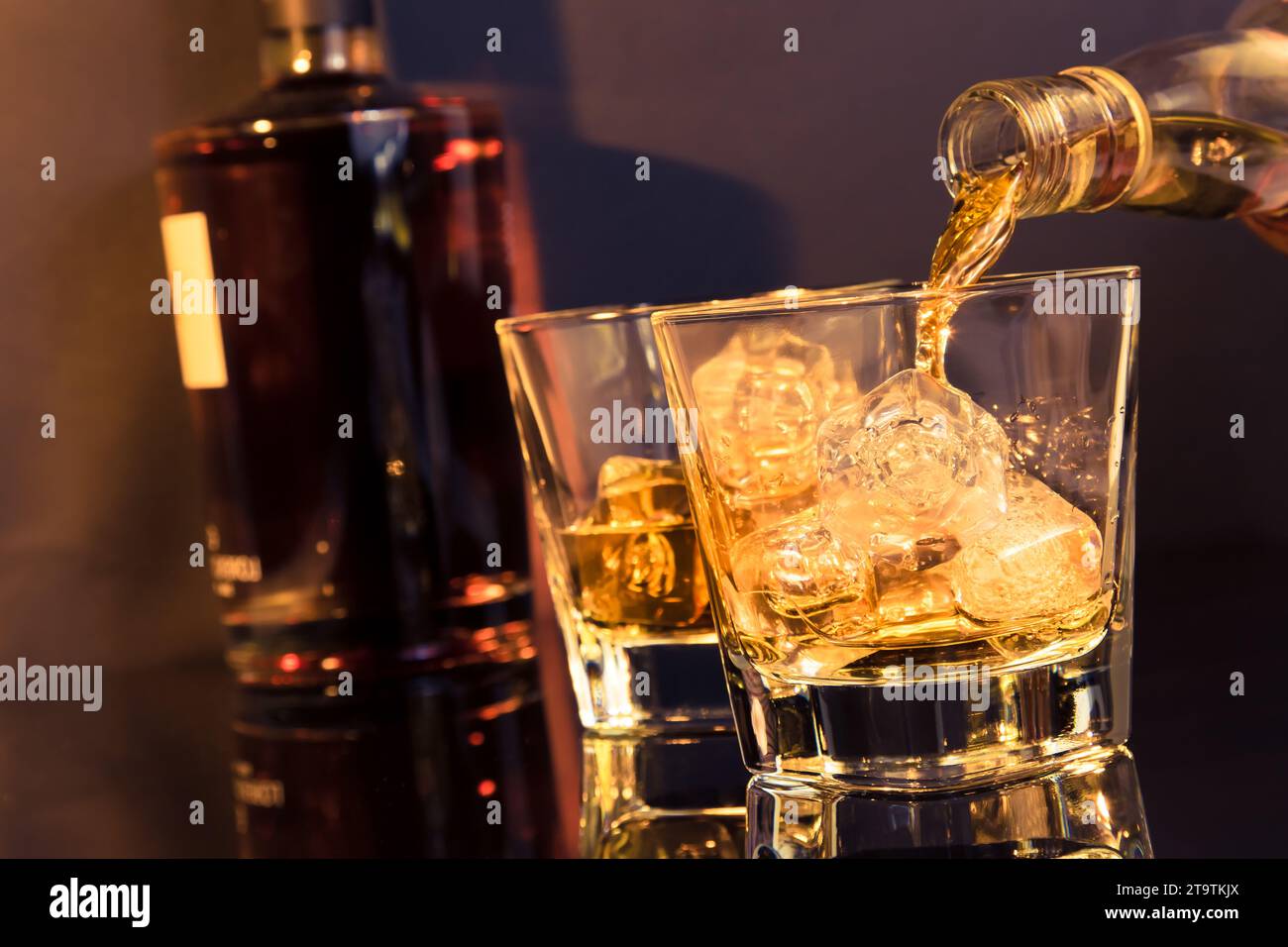 barman pouring whiskey in front of whiskey glass and bottle on black ...