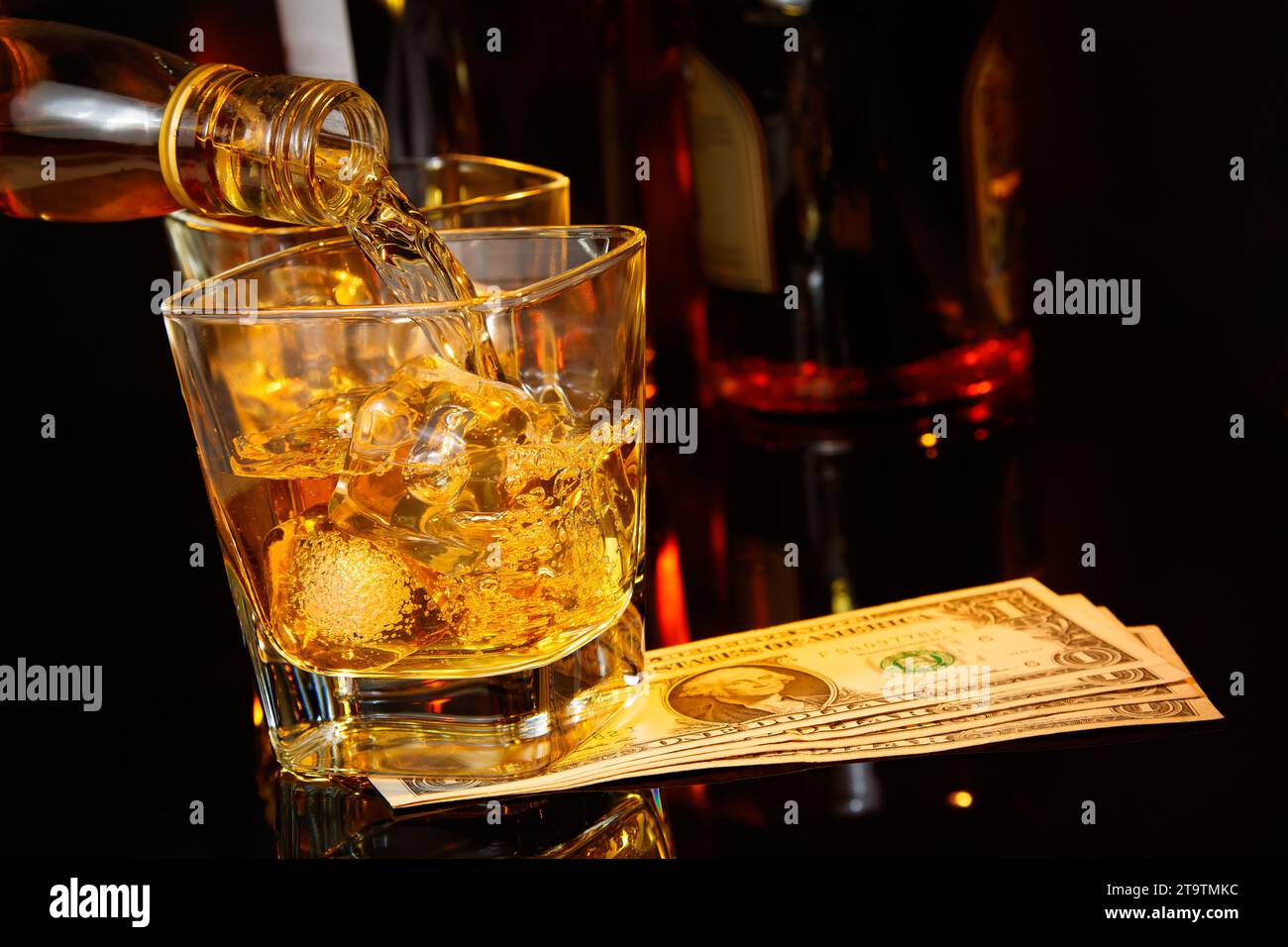 barman pouring whiskey in front of whisky glass and bottles near ...