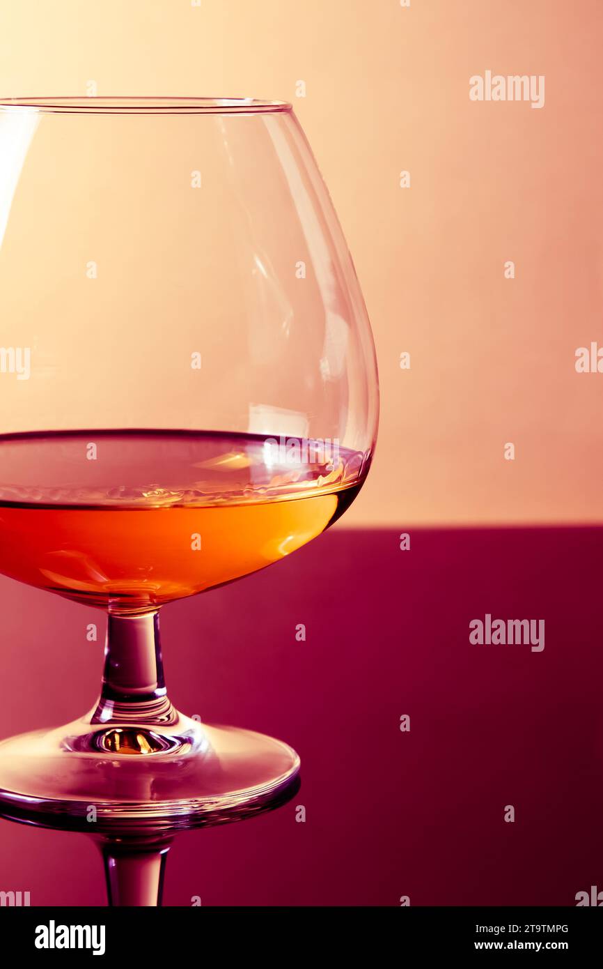 snifter of brandy in elegant typical cognac glass on purple colored ...