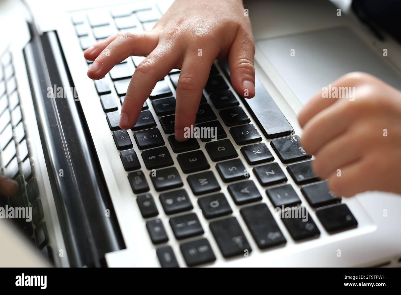 A general view of a young child's hands typing on a laptop keyboard ...
