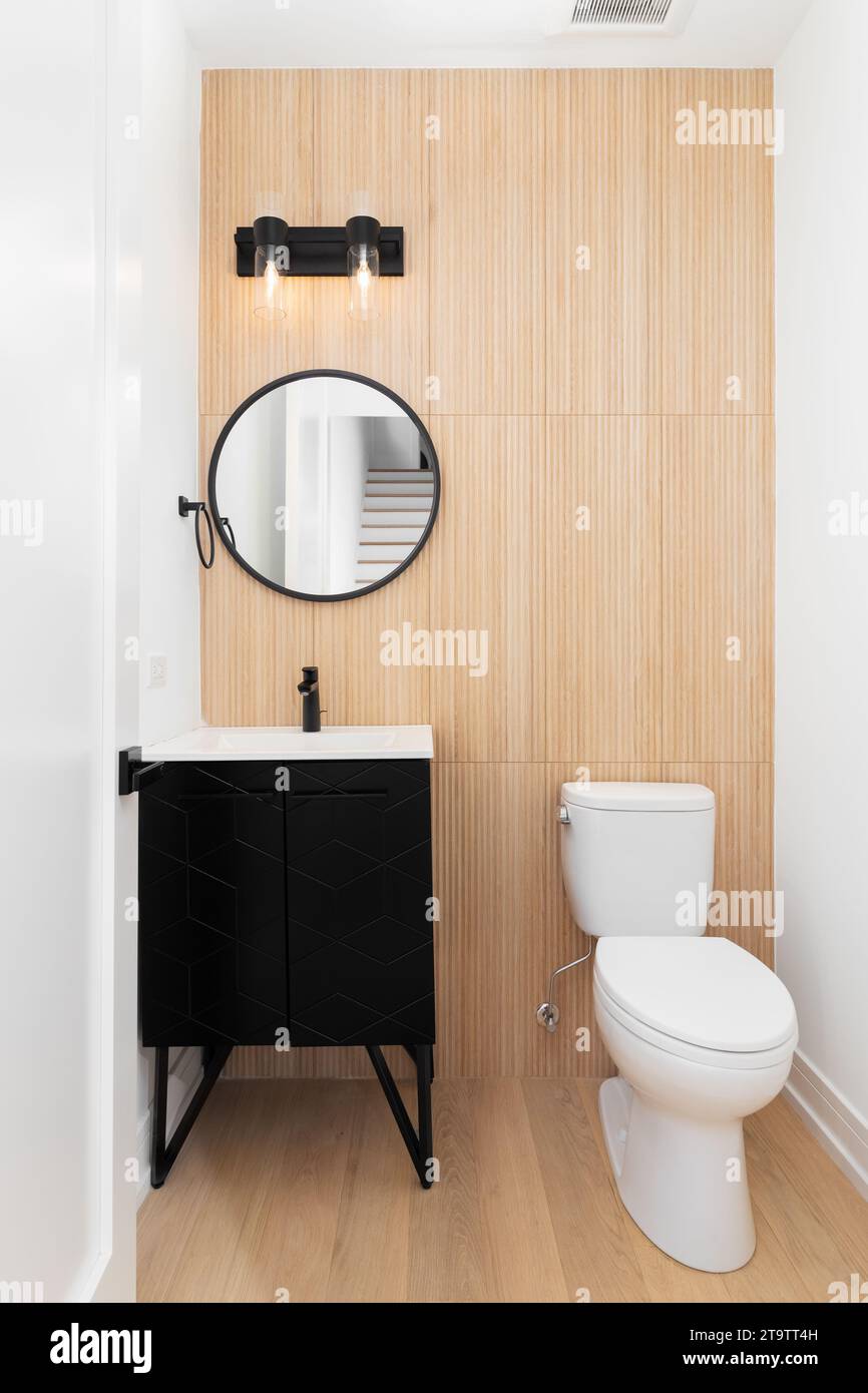 A bathroom with a white oak wood slat wall with a black cabinet and ...