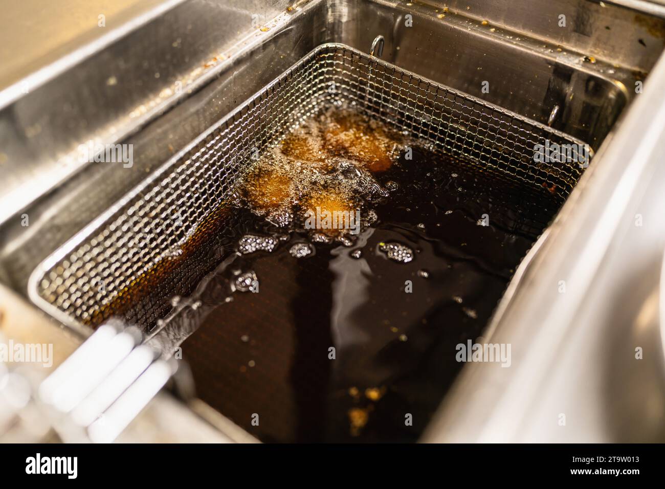 fried potato balls deep frying in deep frying fat at a commercial ...