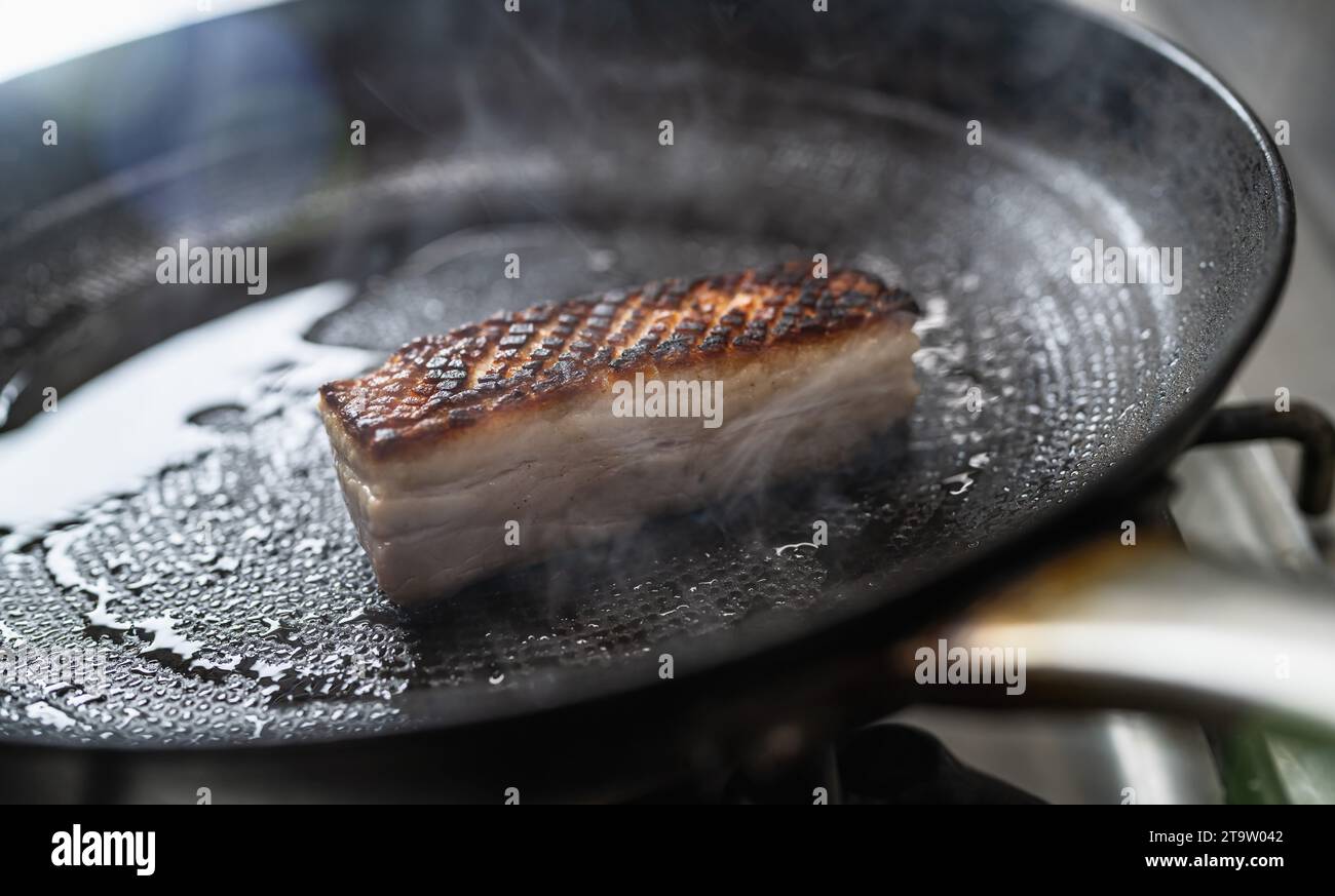 Crispy pork Roast in hot pan with oil at a gas stove in a professional ...