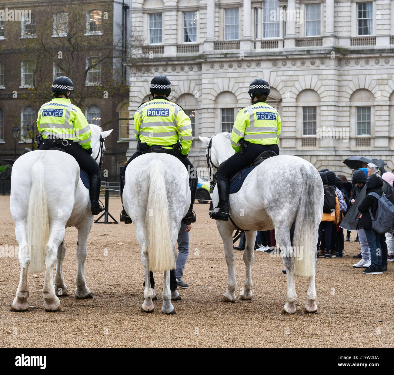 A trio of mounted metropolitan police officers next to a group of ...