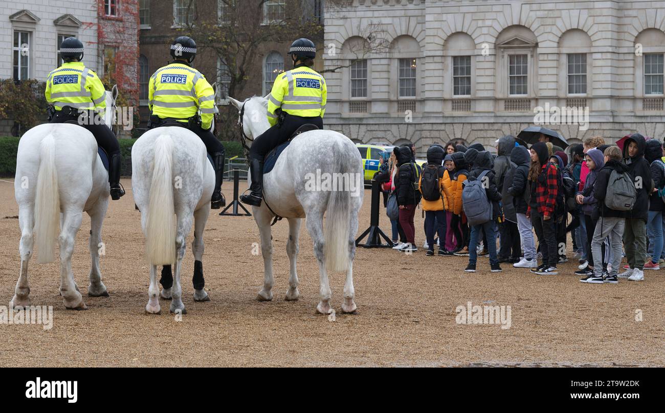 A trio of mounted metropolitan police officers next to a group of ...