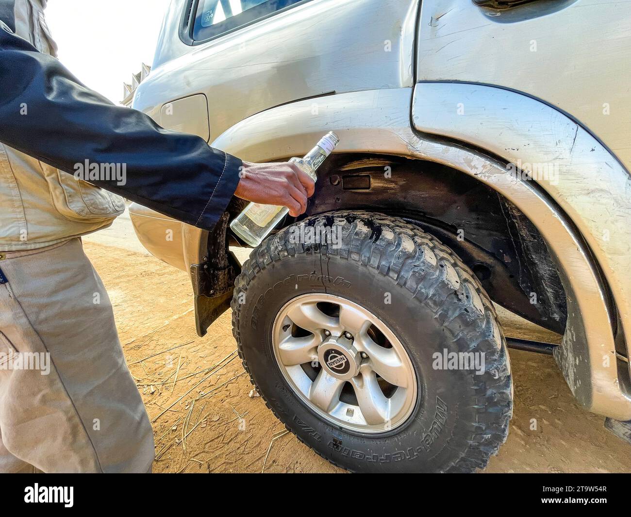 Madagascar, a man pours rum on the car tires as a sign of superstition ...