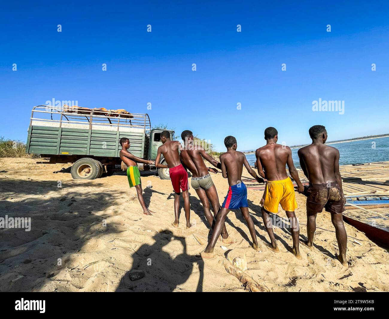 Madagascar, Tsiribihina river, young men tow barge on river Stock Photo ...