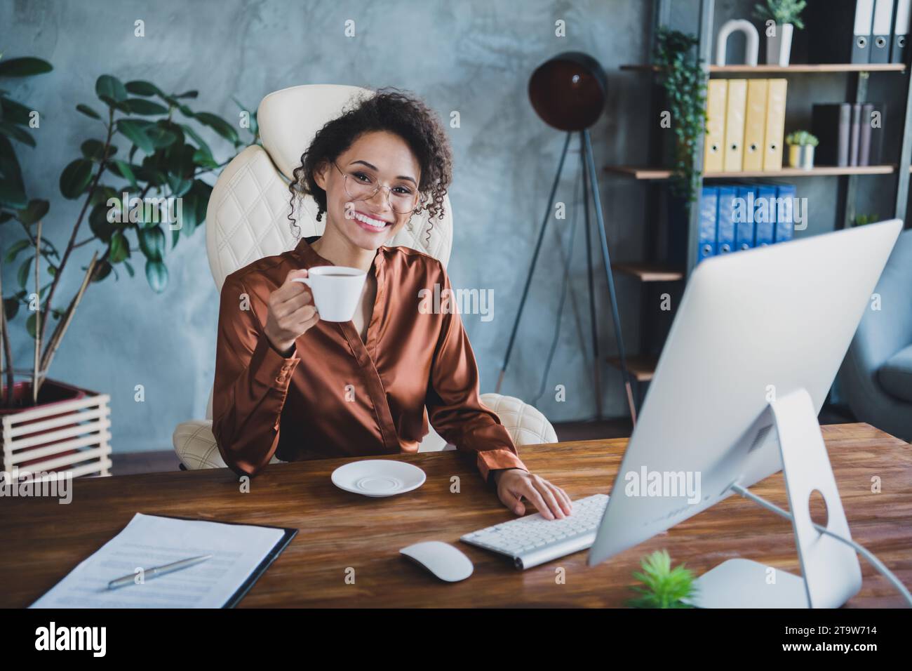 Portrait of gorgeous cheerful economist lady sit chair drink hot coffee ...