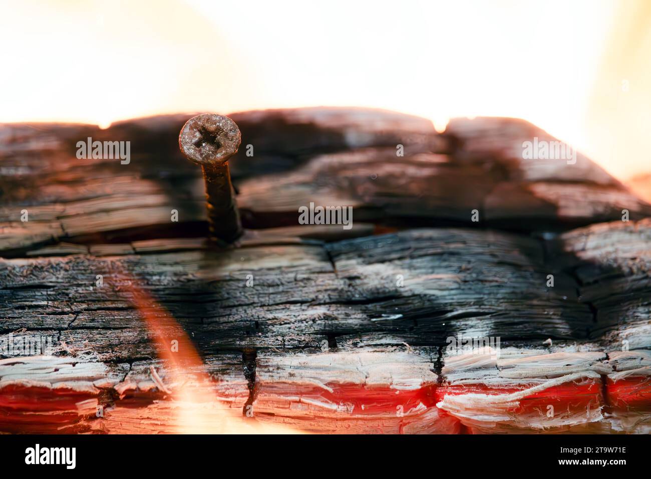 A picture of a pile of wood logs burned to a red and black char, with ...
