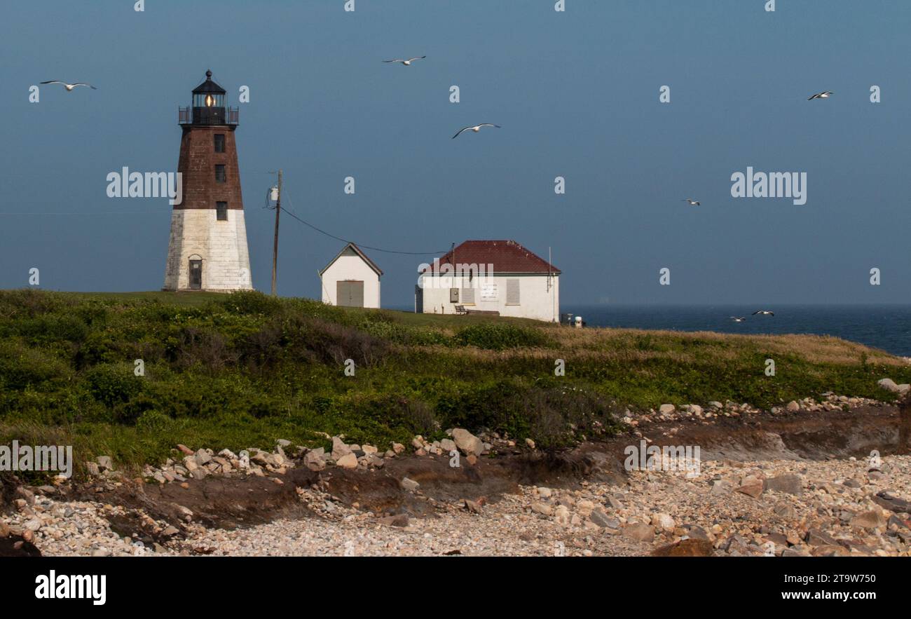 The Point Judith lighthouse sitting on top of a hill next to the ocean ...