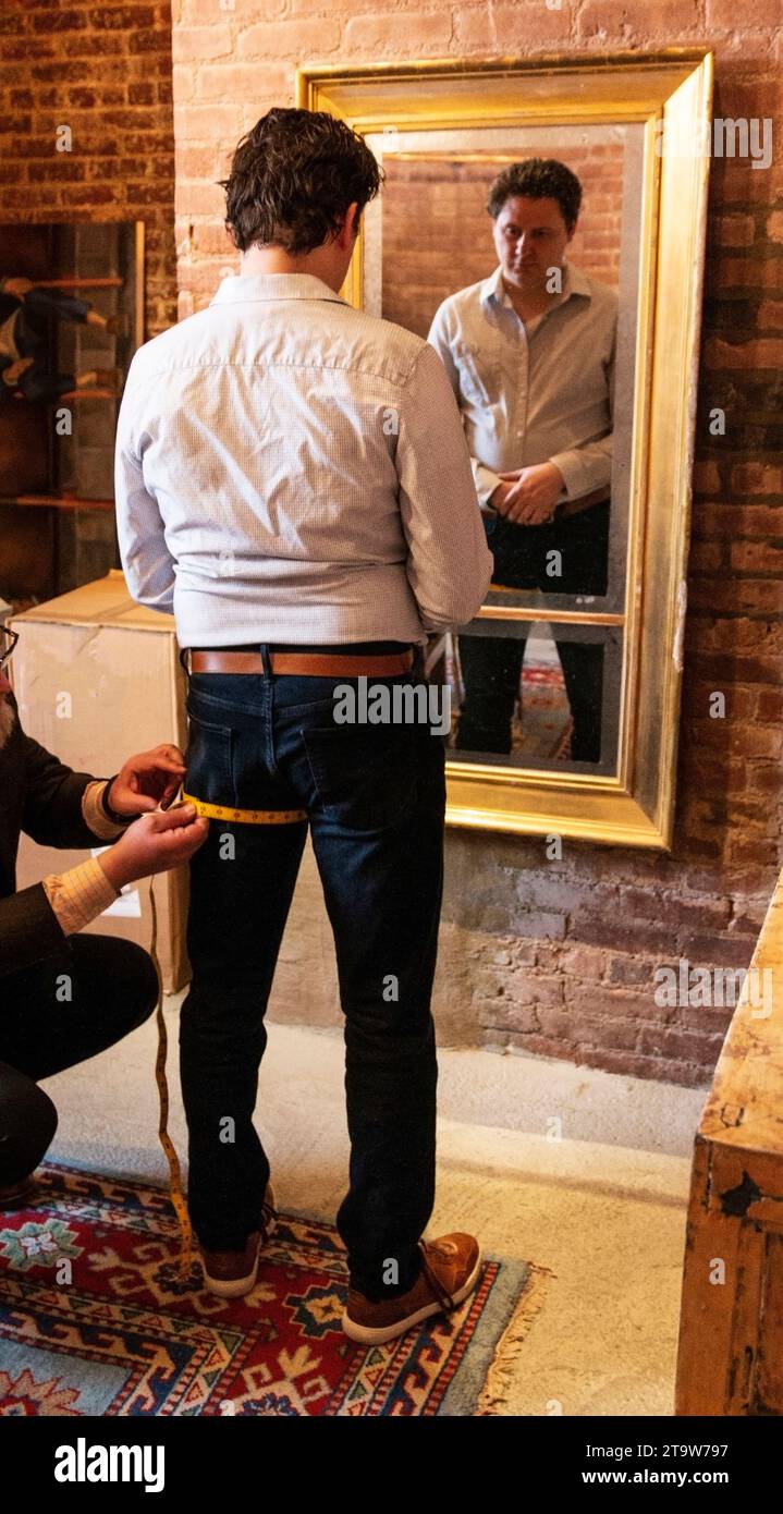 A man is measuring another man's waist and legs with a tape to build a ...