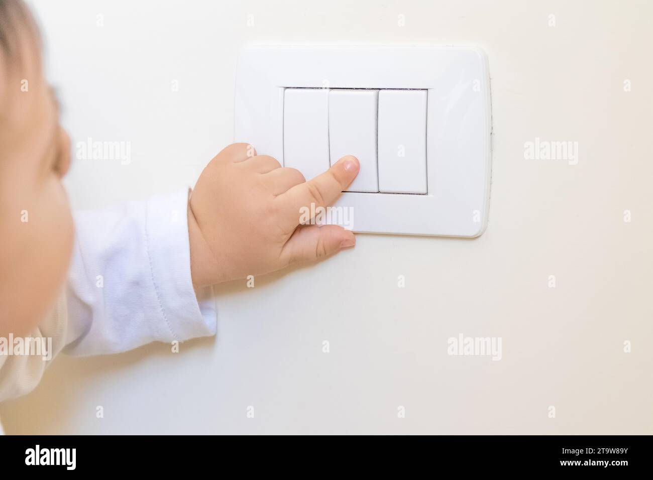 child little boy turning on the white light-switch with his finger of ...