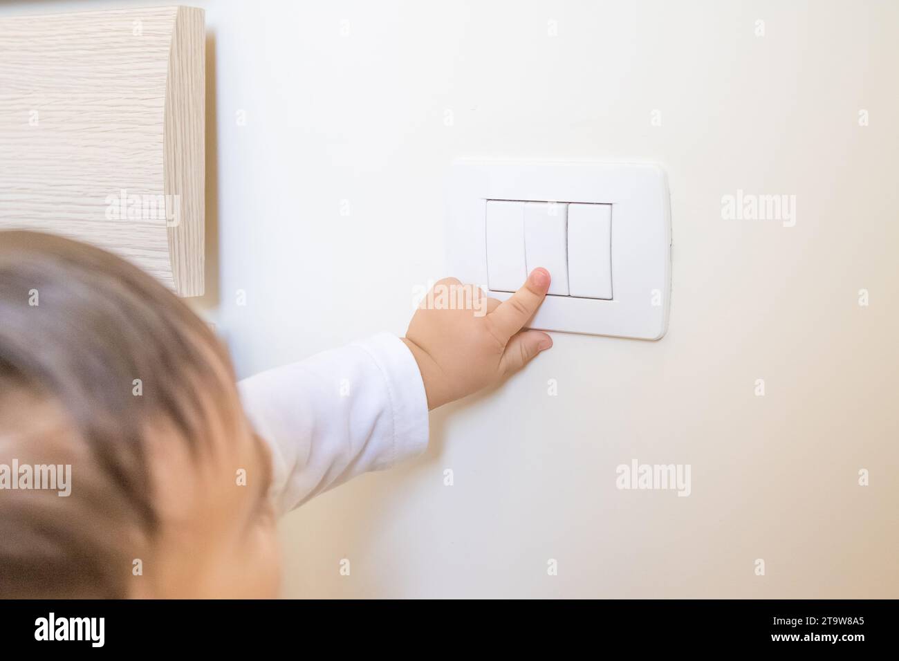 adorable little boy child turning on the white light-switch with his ...