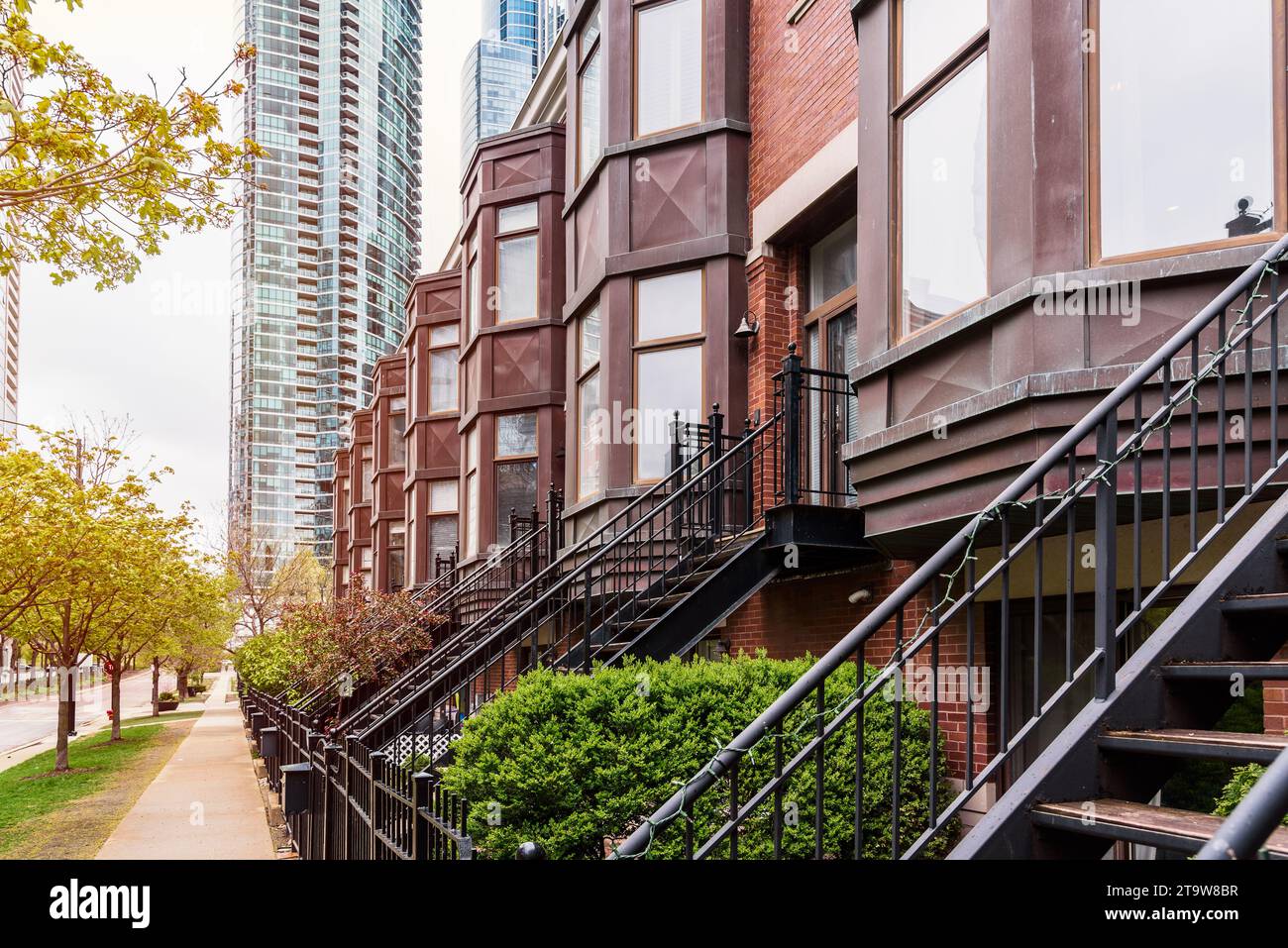 Row houses with metal stairs leading to the fron door along a tree ...