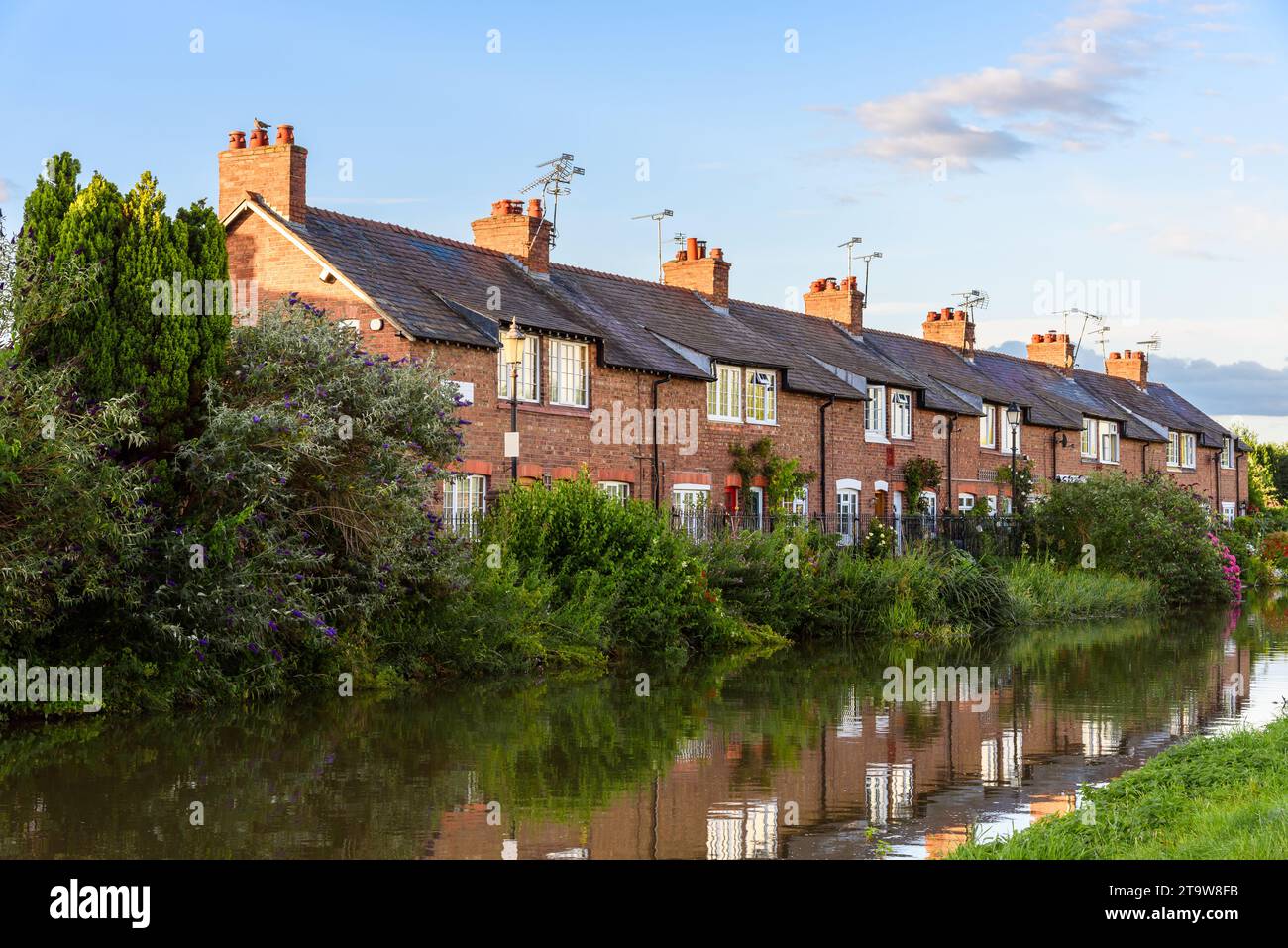 Row of traditional British terraced houses along a canal under a clear ...
