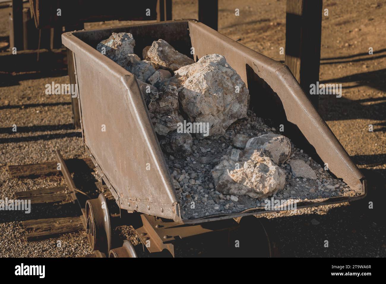 A large yellow dump truck loaded with rocks is parked on railroad ...
