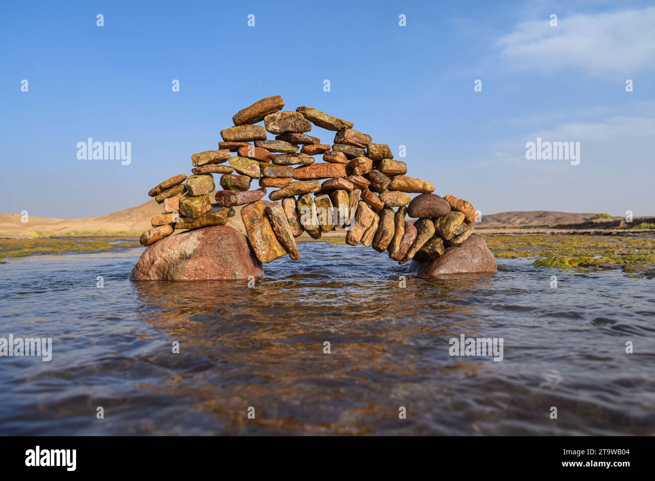 A picturesque stone bridge arches over a tranquil blue body of water ...
