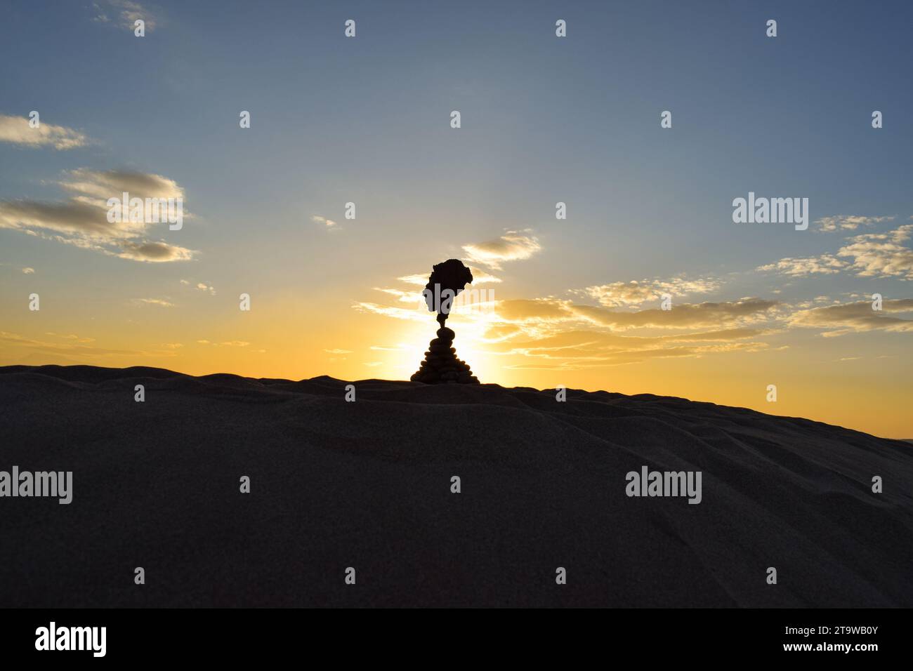 A person stands atop a sand dune, their silhouette framed by a radiant ...