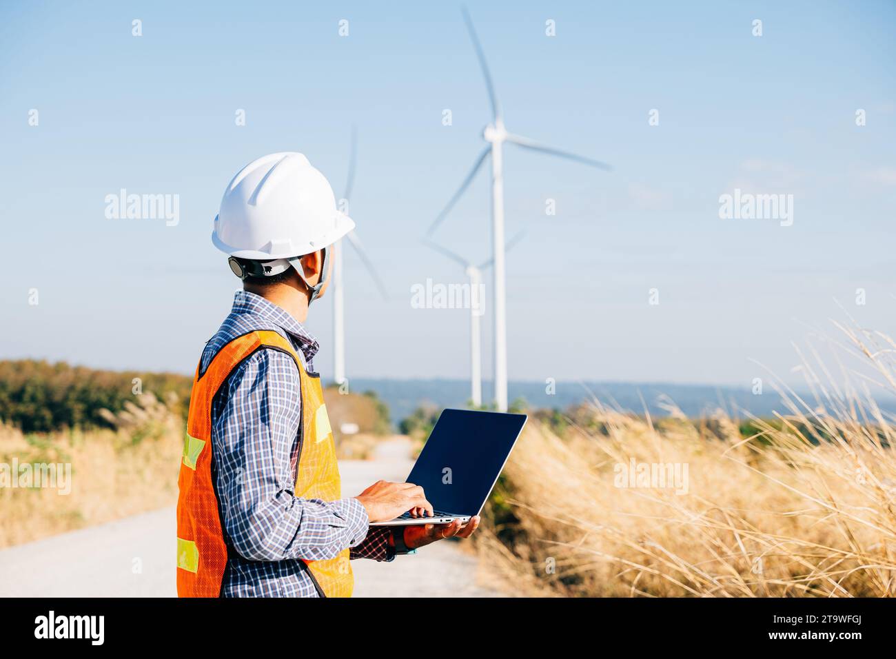 Engineer with laptop by wind turbines Stock Photo - Alamy