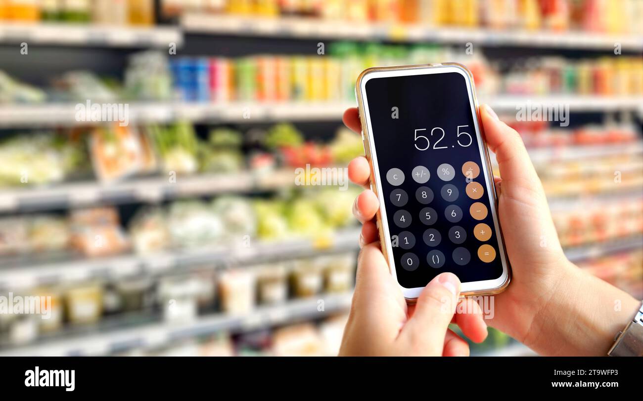 Calculator on mobile phone screen in customer's hands. Young woman does ...