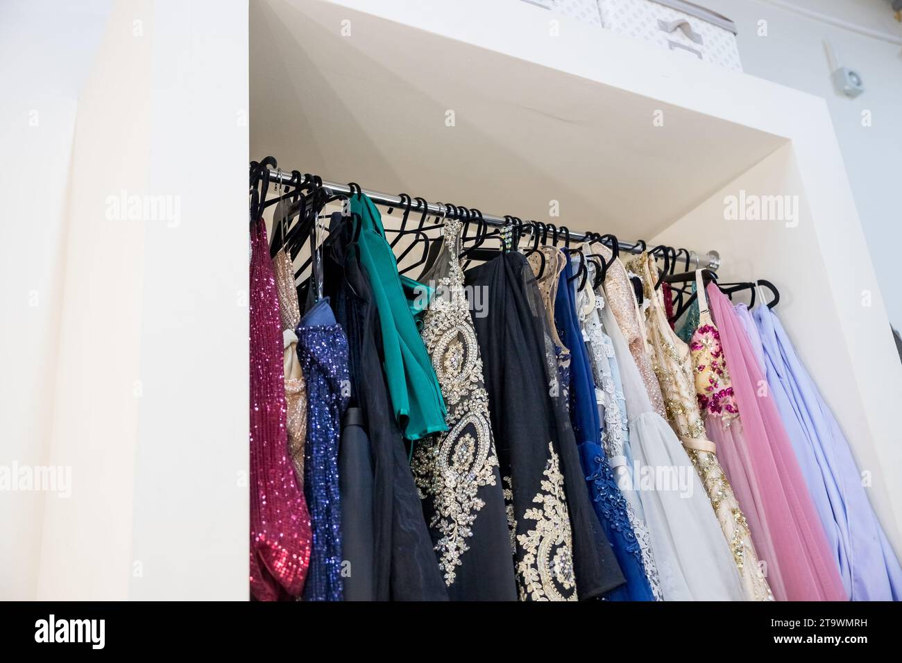 Different evening gown dresses on hangers in boutique. Pink, blue and ...