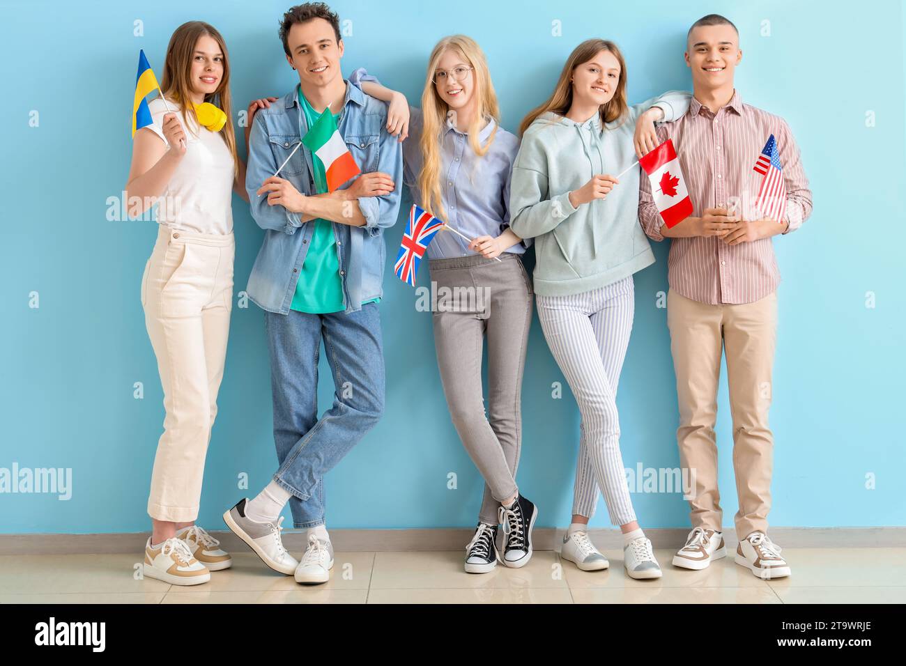 Group of students with flags of different countries near blue wall ...