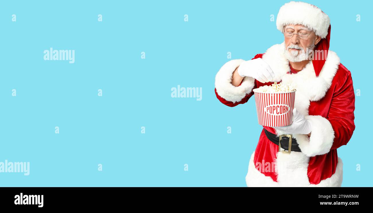 Santa Claus eating popcorn on light blue background with space for text ...