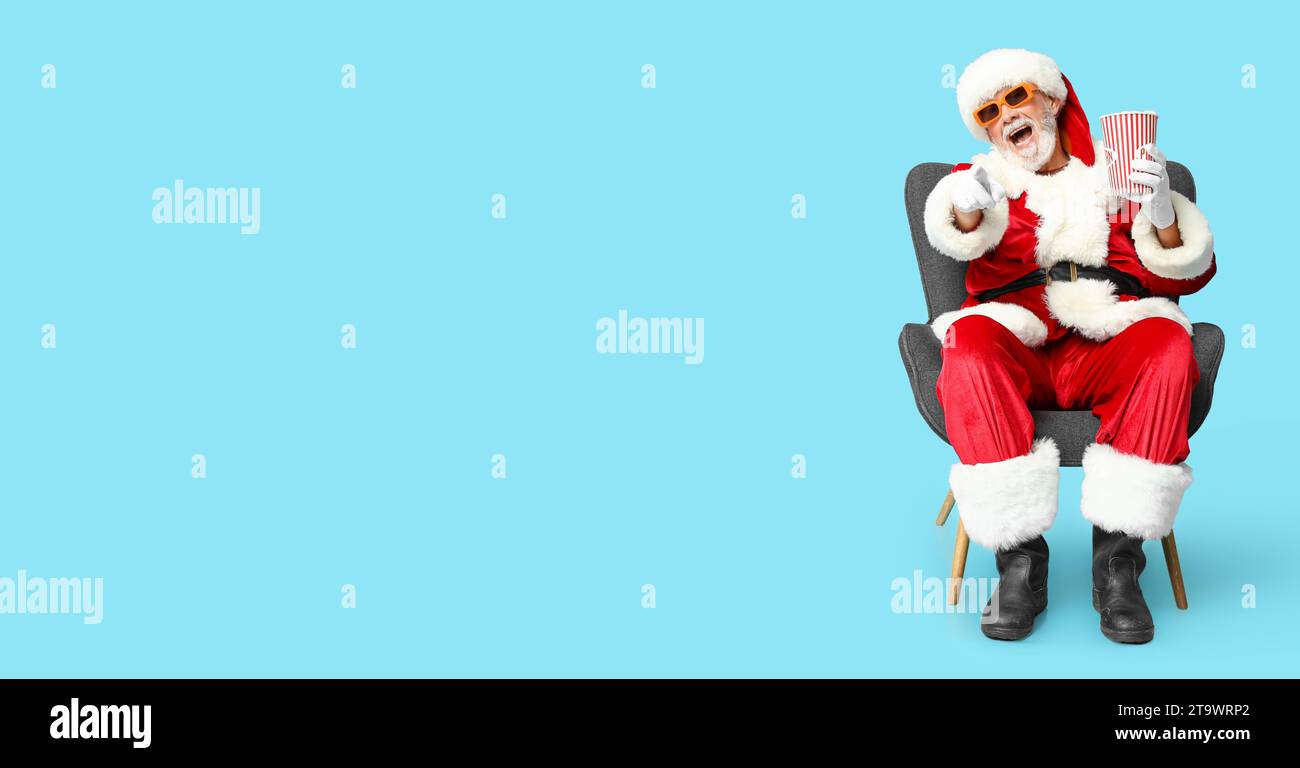 Santa Claus with popcorn watching Christmas comedy against light blue ...