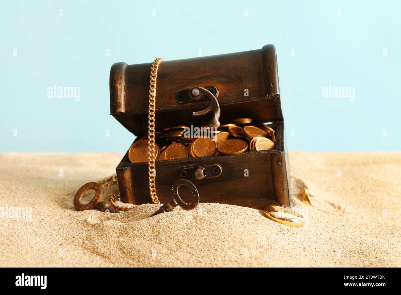 Old chest with treasures and keys on sand against blue background Stock ...