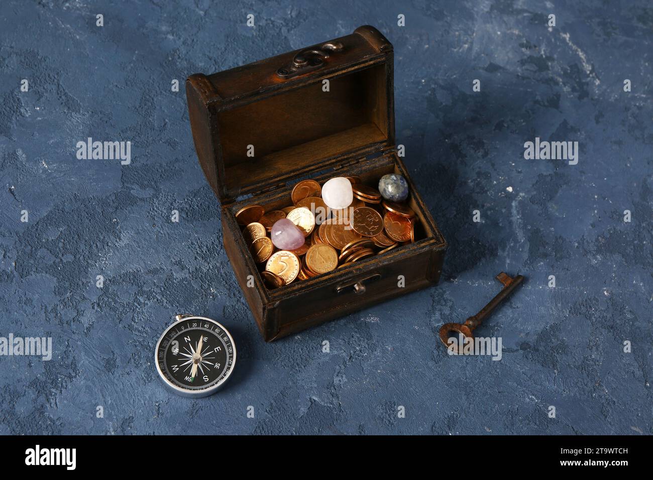 Old chest with treasures, key and compass on grunge blue background ...
