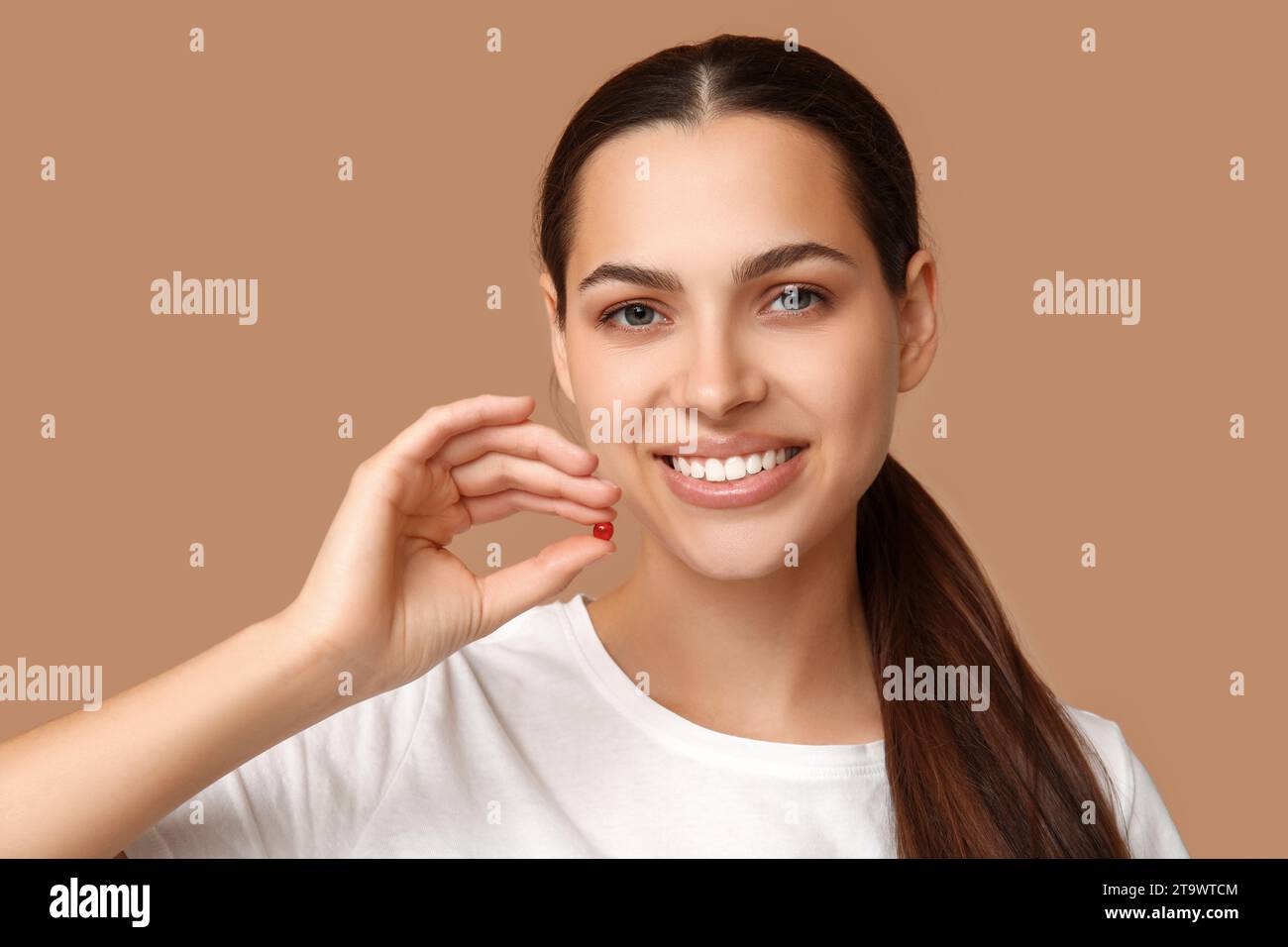 Pretty young woman taking vitamin A capsule on beige background Stock ...