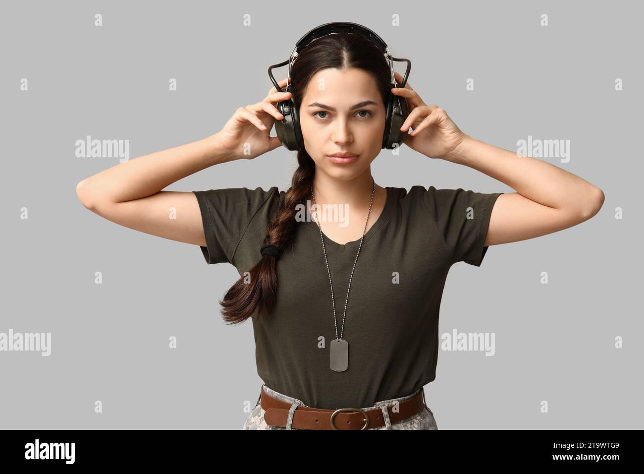 Female soldier in uniform with tactical headset on grey background ...