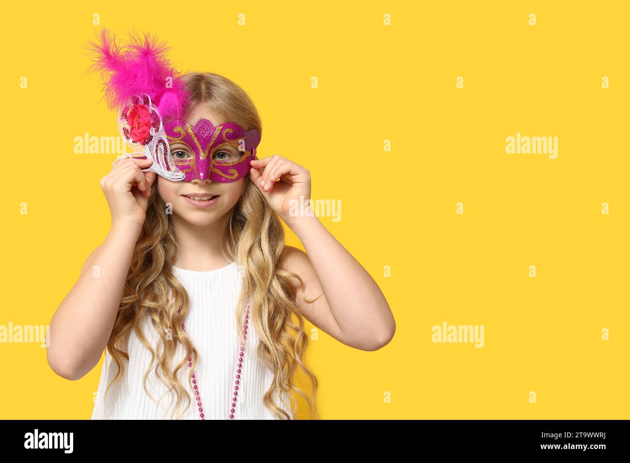 Adorable little girl wearing carnival mask on yellow background Stock ...