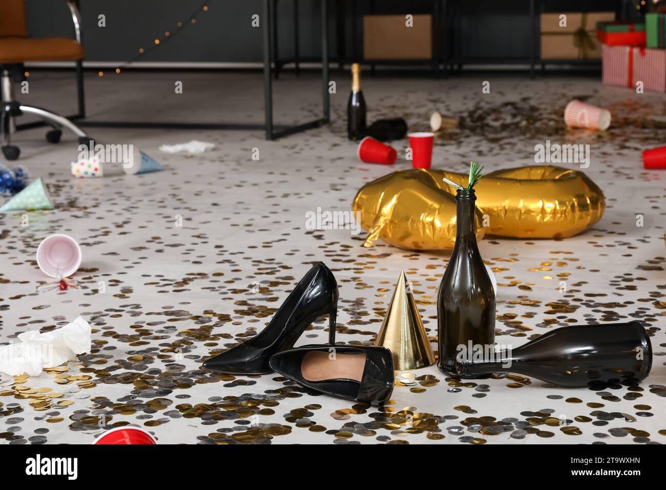 Heels with bottles and confetti on floor in messy office after New Year ...