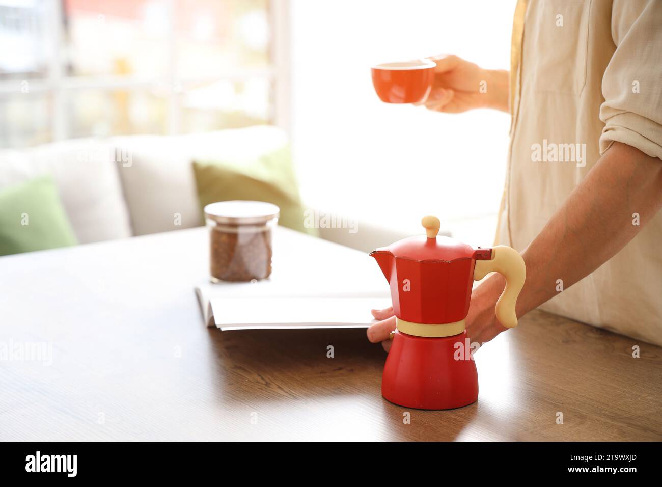 Man drinking espresso while reading magazine at table with geyser ...