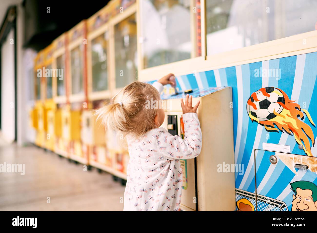 Little girl pulls the lever classic claw grabber game machine with toys ...
