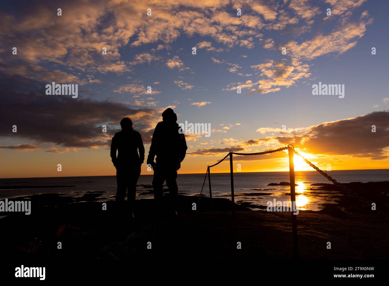 two people watching a sunset by the sea in iceland. sky of clouds and ...