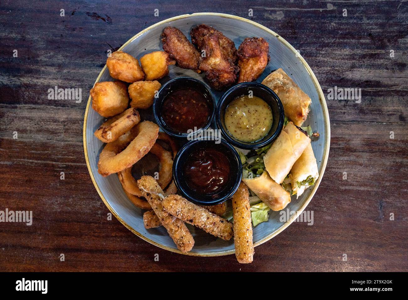 a birds eye view of a plate of deep fried appetizer combo served with ...